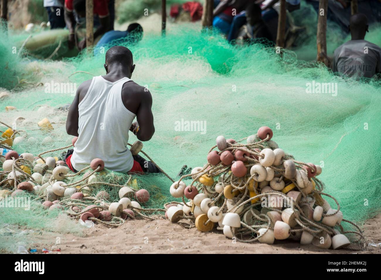 Man repairing fishing net on Tanji beach, The Gambia Stock Photo - Alamy