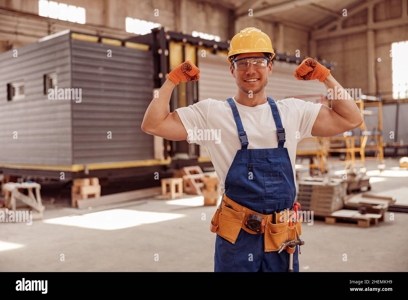 Cheerful male worker demonstrating his strong muscular arms Stock Photo ...