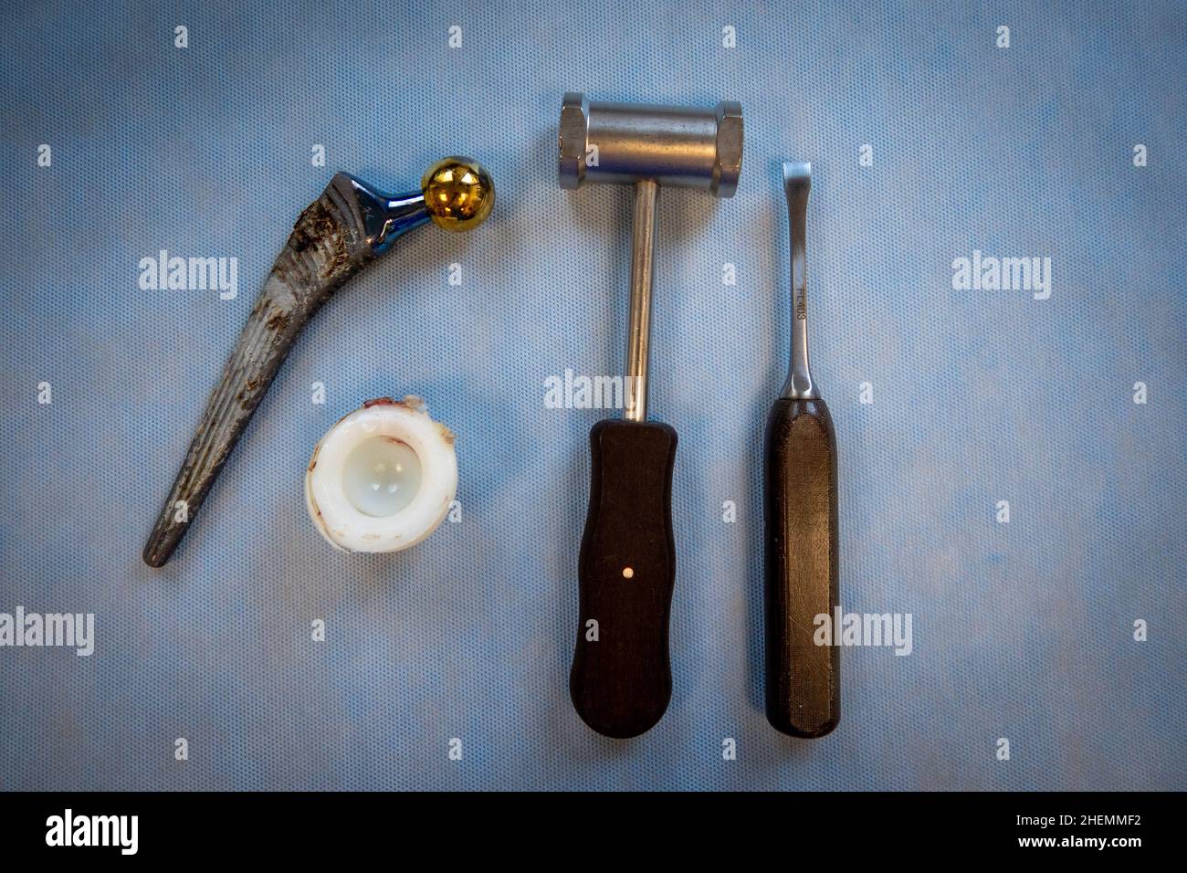 complete explanted hip prosthesis lies next to a hammer and a chisel ...