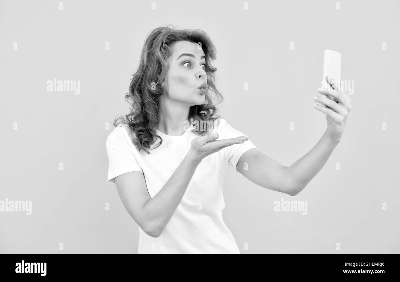 Girl make hand kissing gesture to camera phone yellow background ...