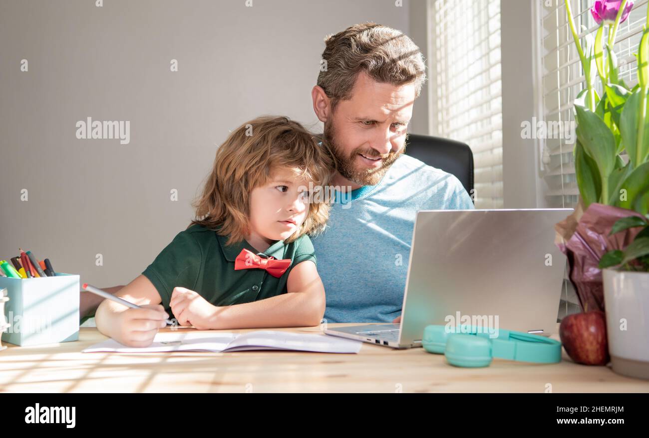 back to school. smiling father and son use computer at home. family and ...