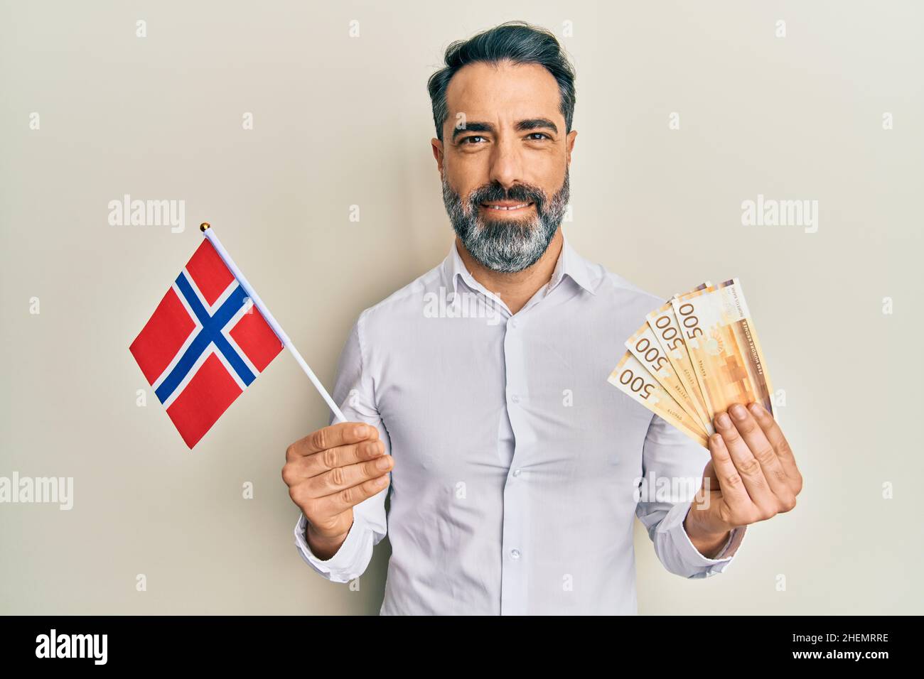 Middle age man with beard and grey hair holding norway flag and krone ...