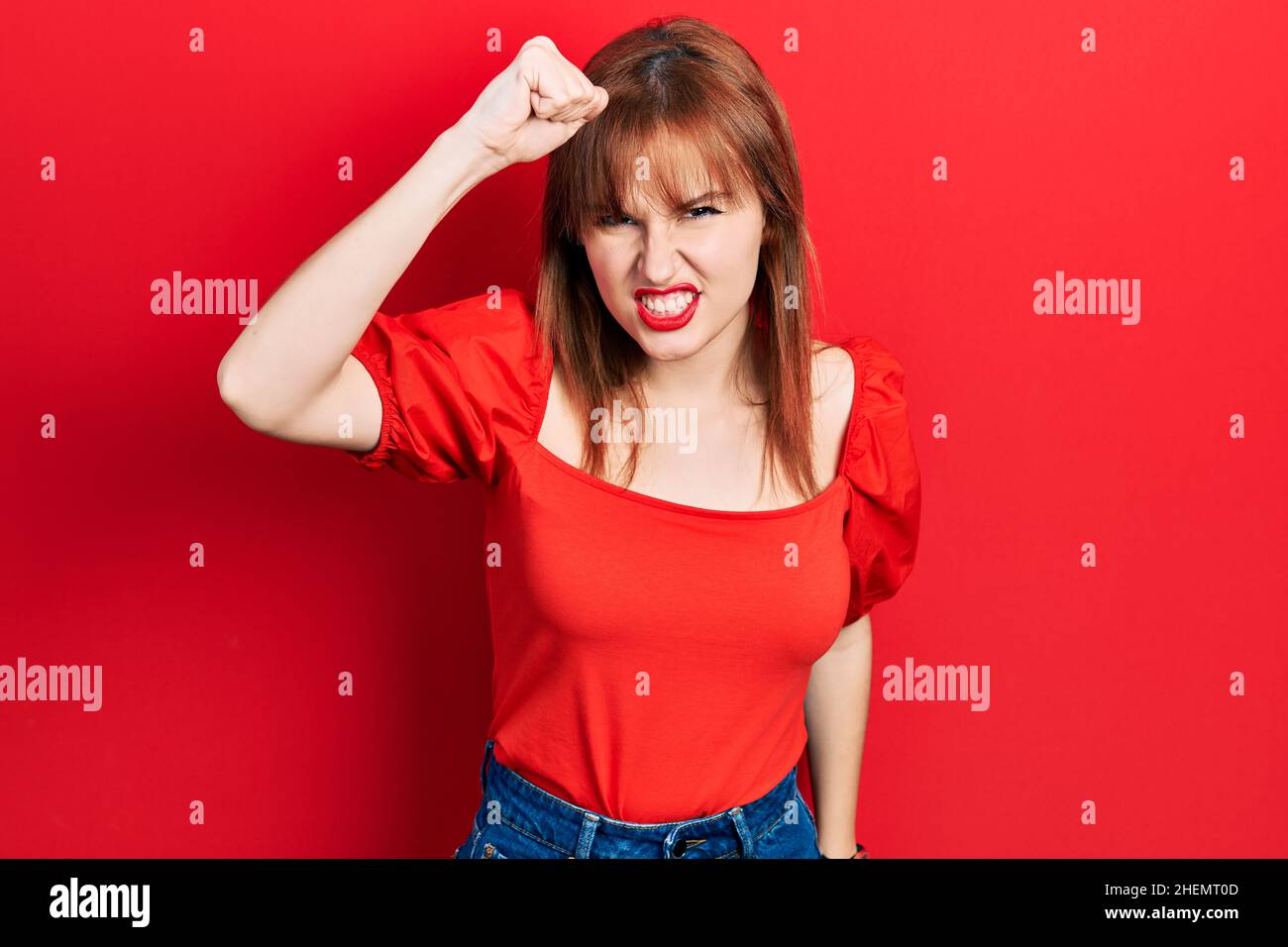 Redhead young woman wearing casual red t shirt angry and mad raising ...