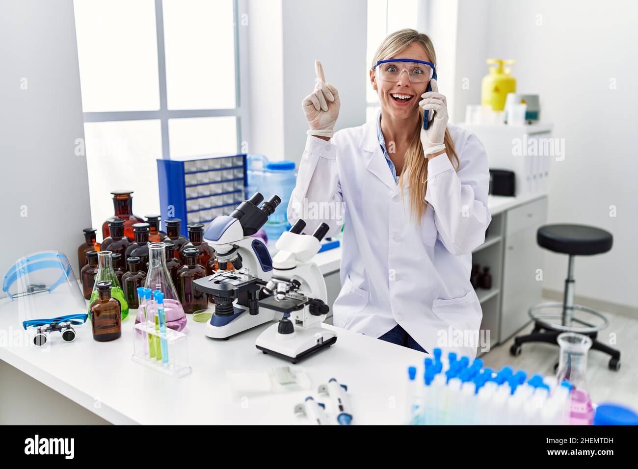 Beautiful woman working at scientist laboratory speaking on the phone ...