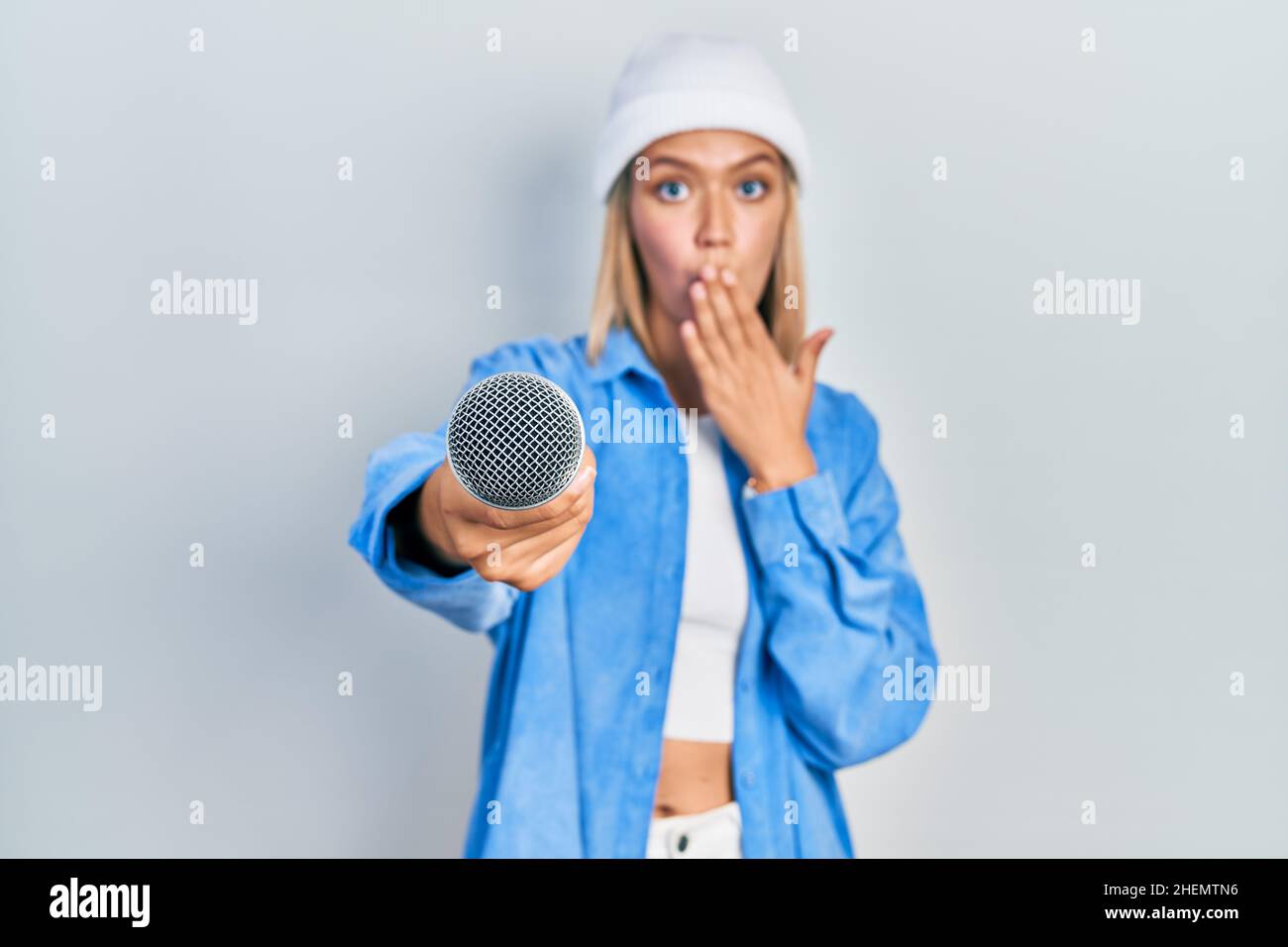 Beautiful blonde woman holding reporter microphone to the camera ...