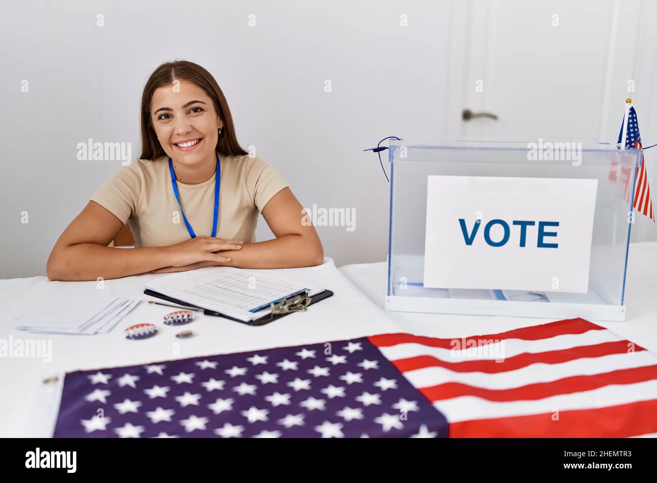 Young brunette woman at political election sitting by ballot happy face ...