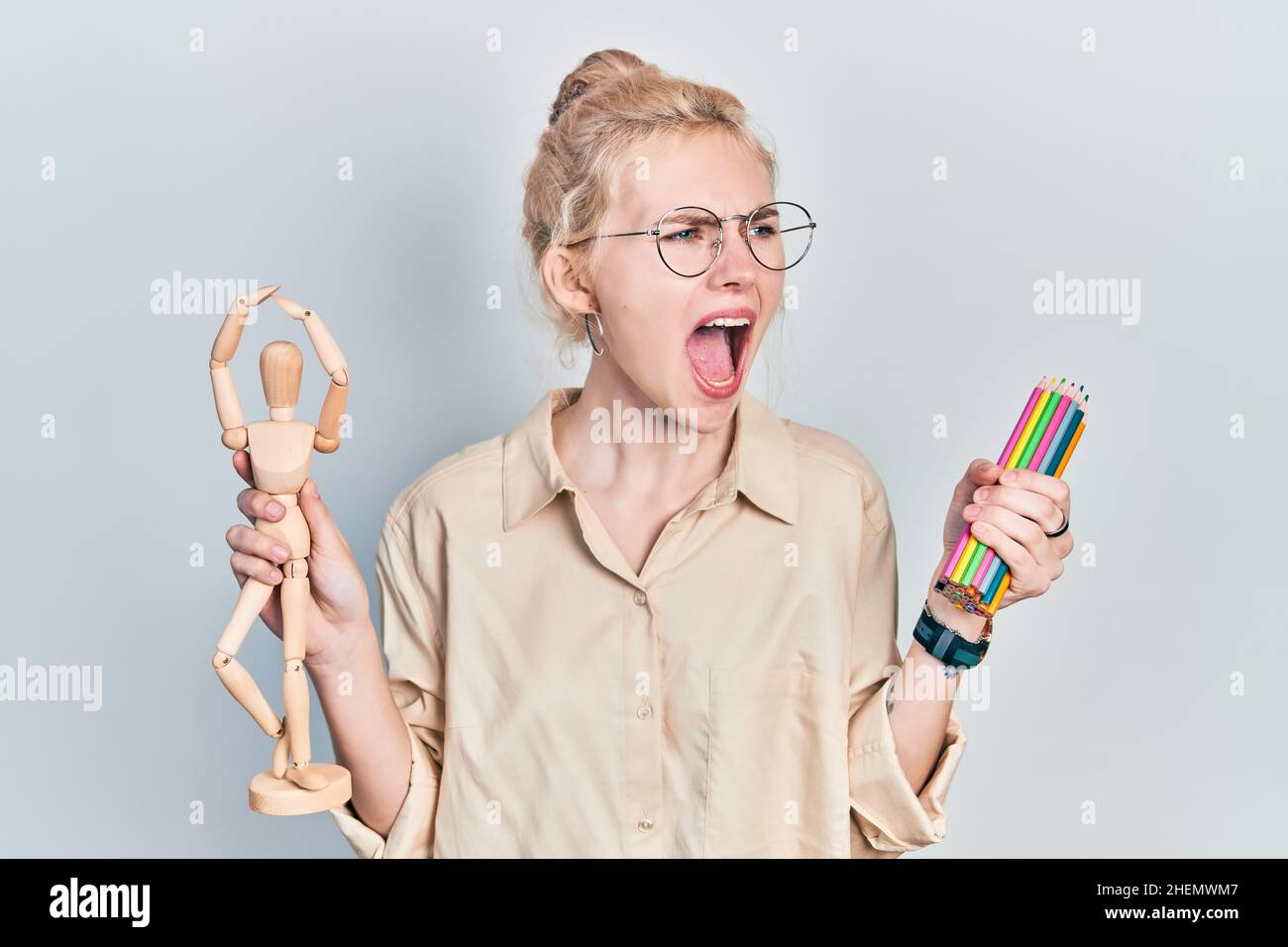 Beautiful caucasian woman with blond hair holding small wooden manikin ...