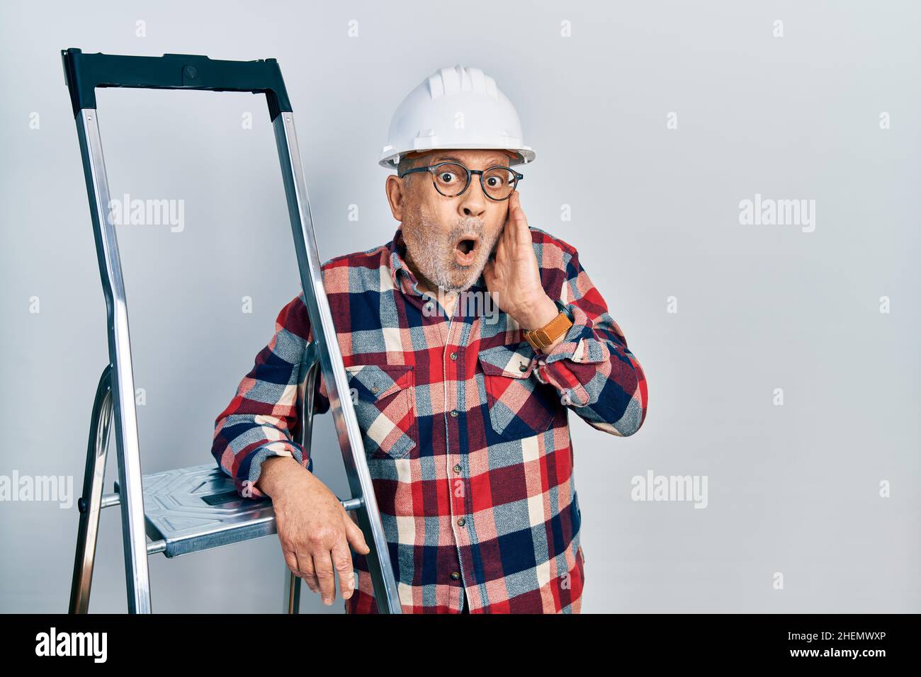 Handsome mature handyman close to construction stairs wearing hardhat ...