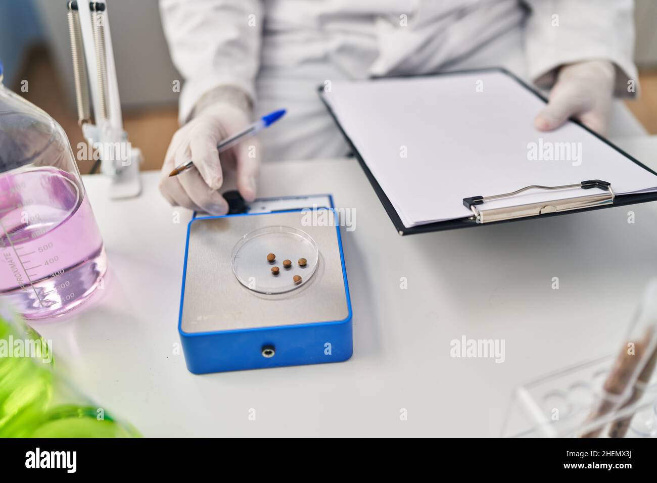 Young hispanic man wearing scientist uniform measuring sample at ...