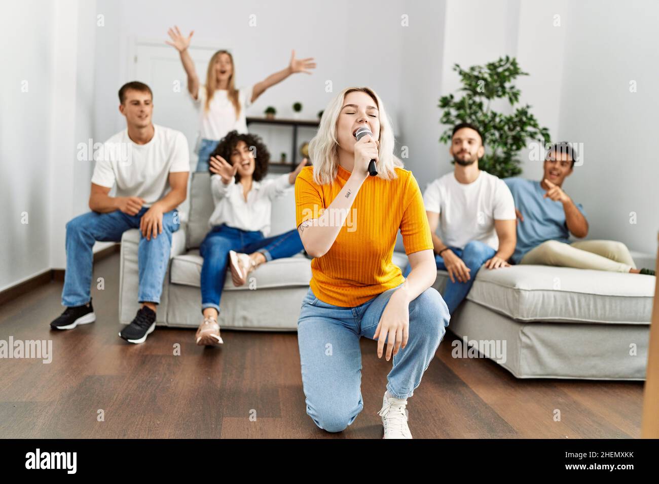 Group of young friends having party singing song using microphone at ...