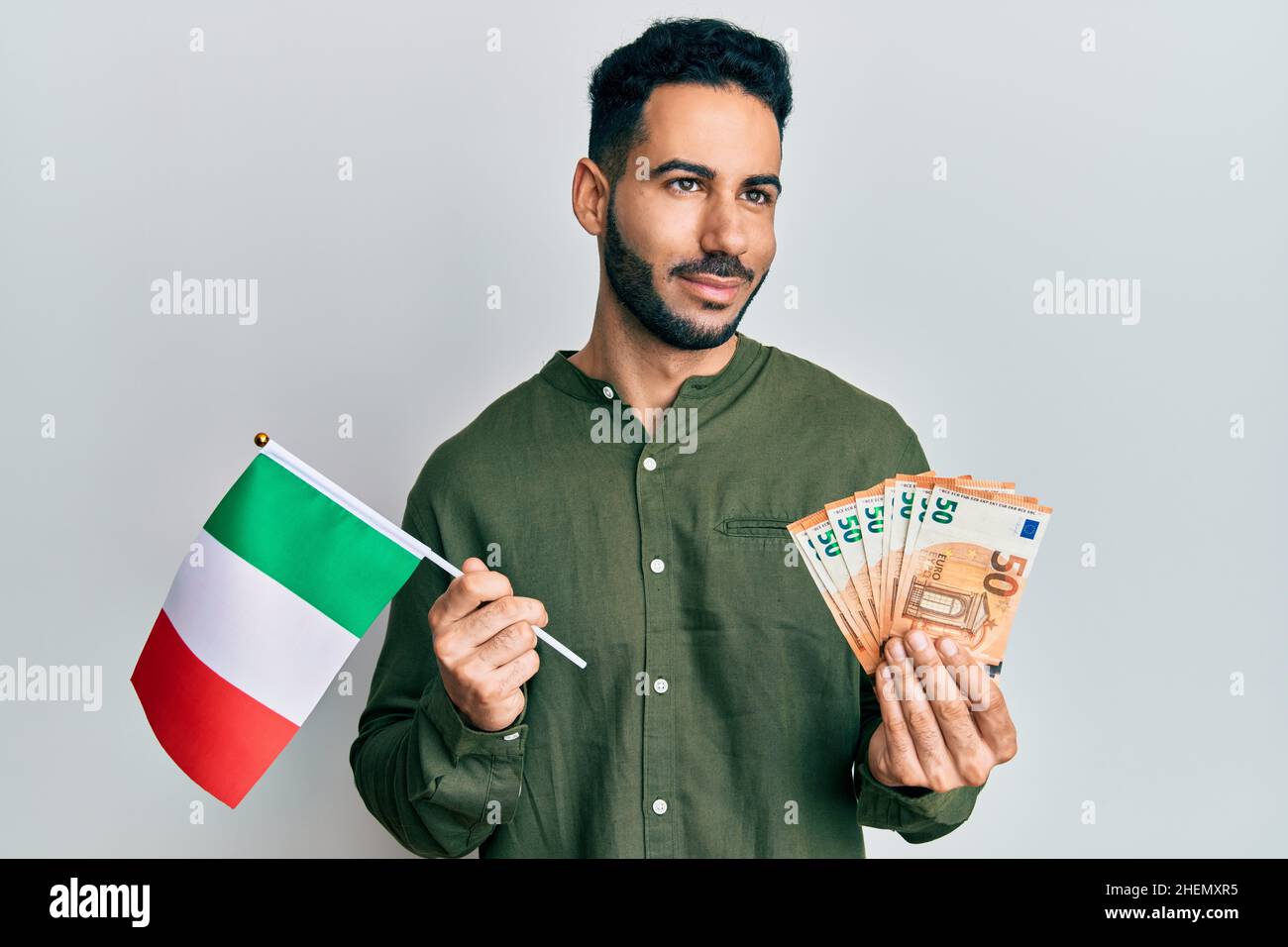Young hispanic man holding italy flag and euros banknotes smiling ...