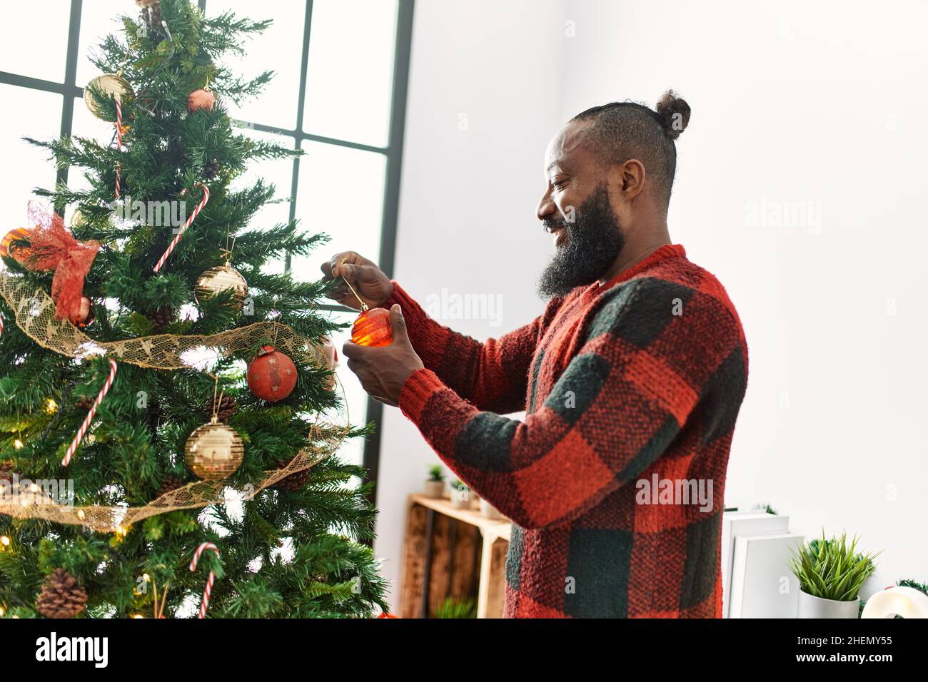 Young african american man smiling confident decorating christmas tree ...