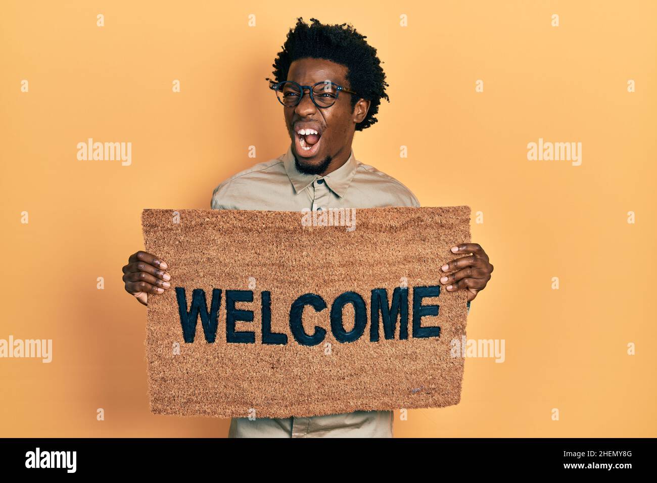 Young african american man holding welcome doormat angry and mad ...