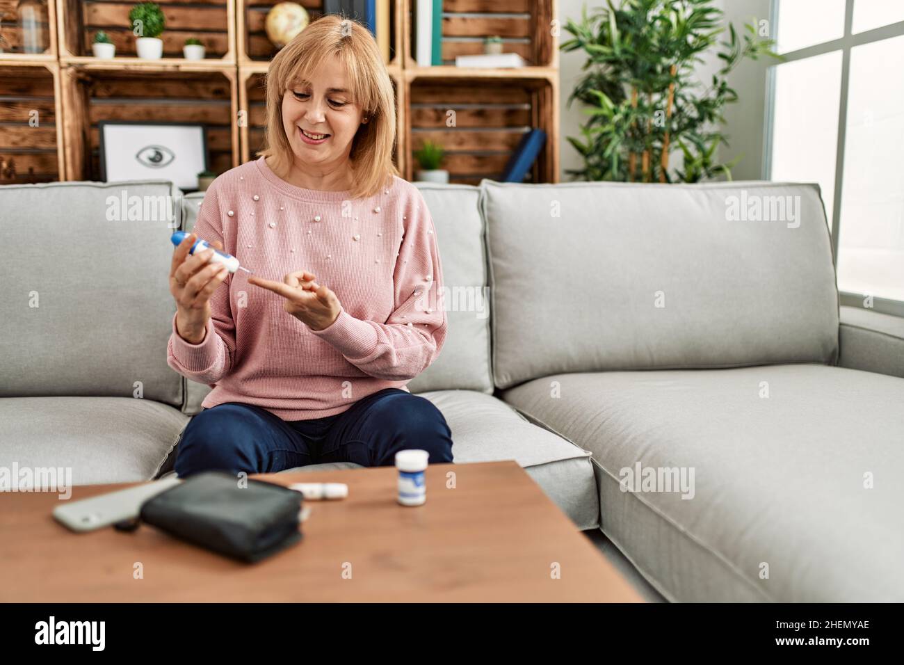 Middle age diabetic woman measuiring glucose using glucometer at home ...