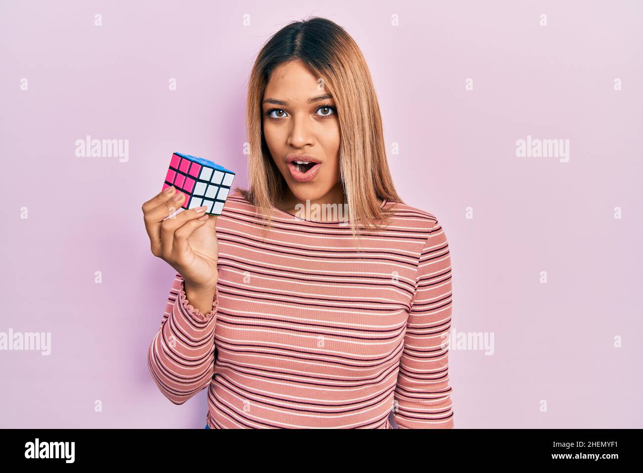 Beautiful hispanic woman playing colorful puzzle cube intelligence game ...