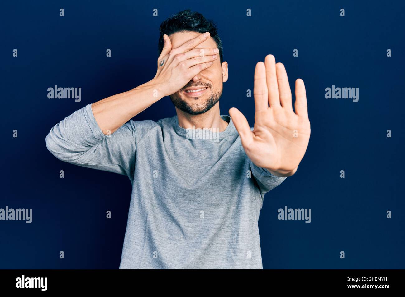 Young hispanic man wearing casual clothes covering eyes with hands and ...