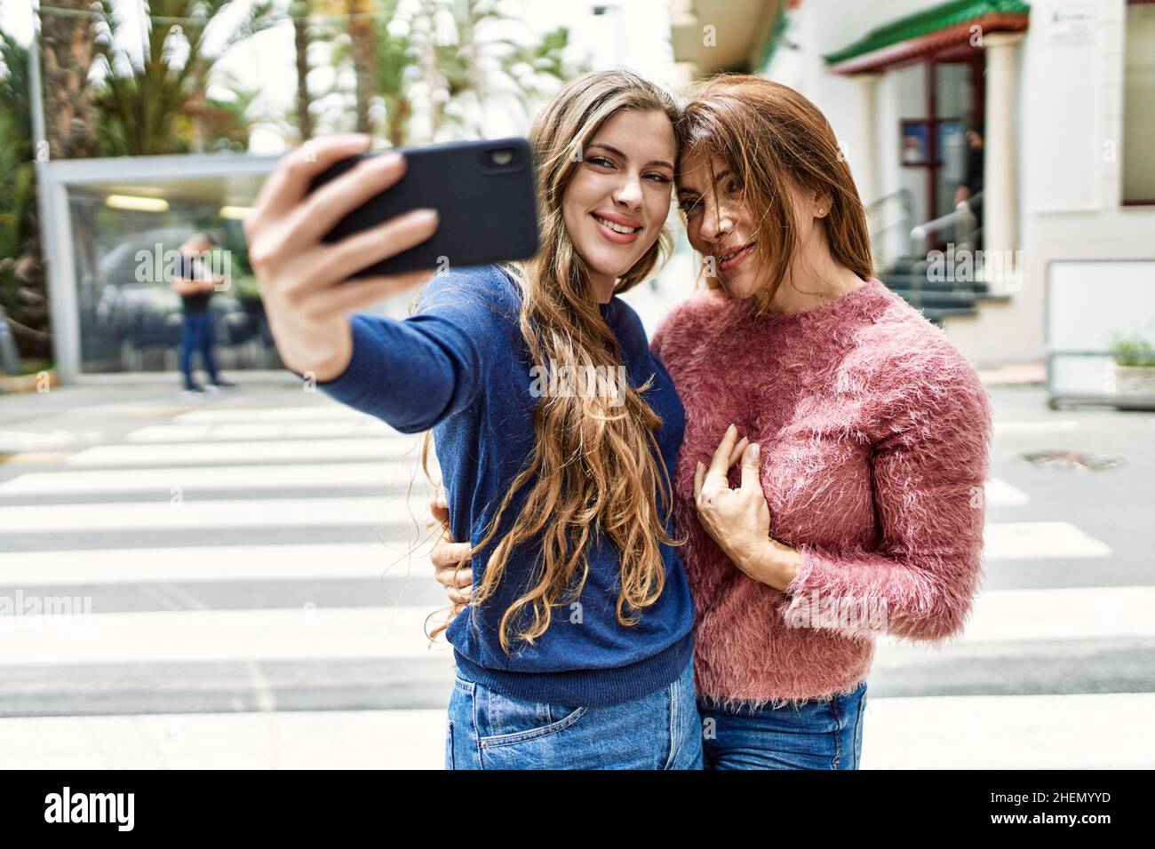 Mother and daughter hugging each other and making selfie by the smartphone at street Stock Photo ...