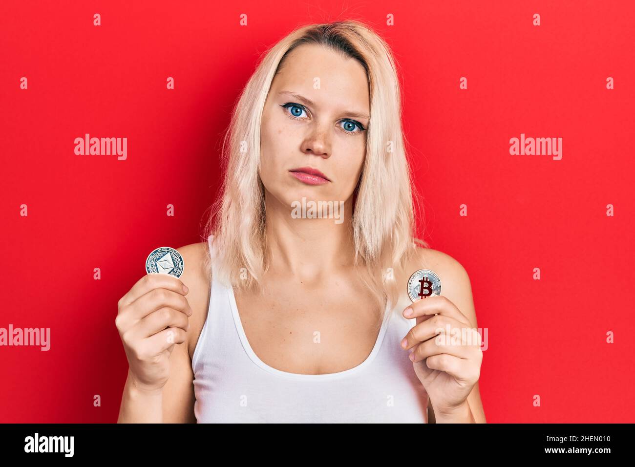 Beautiful caucasian blonde woman holding virtual currency ethereum coin ...