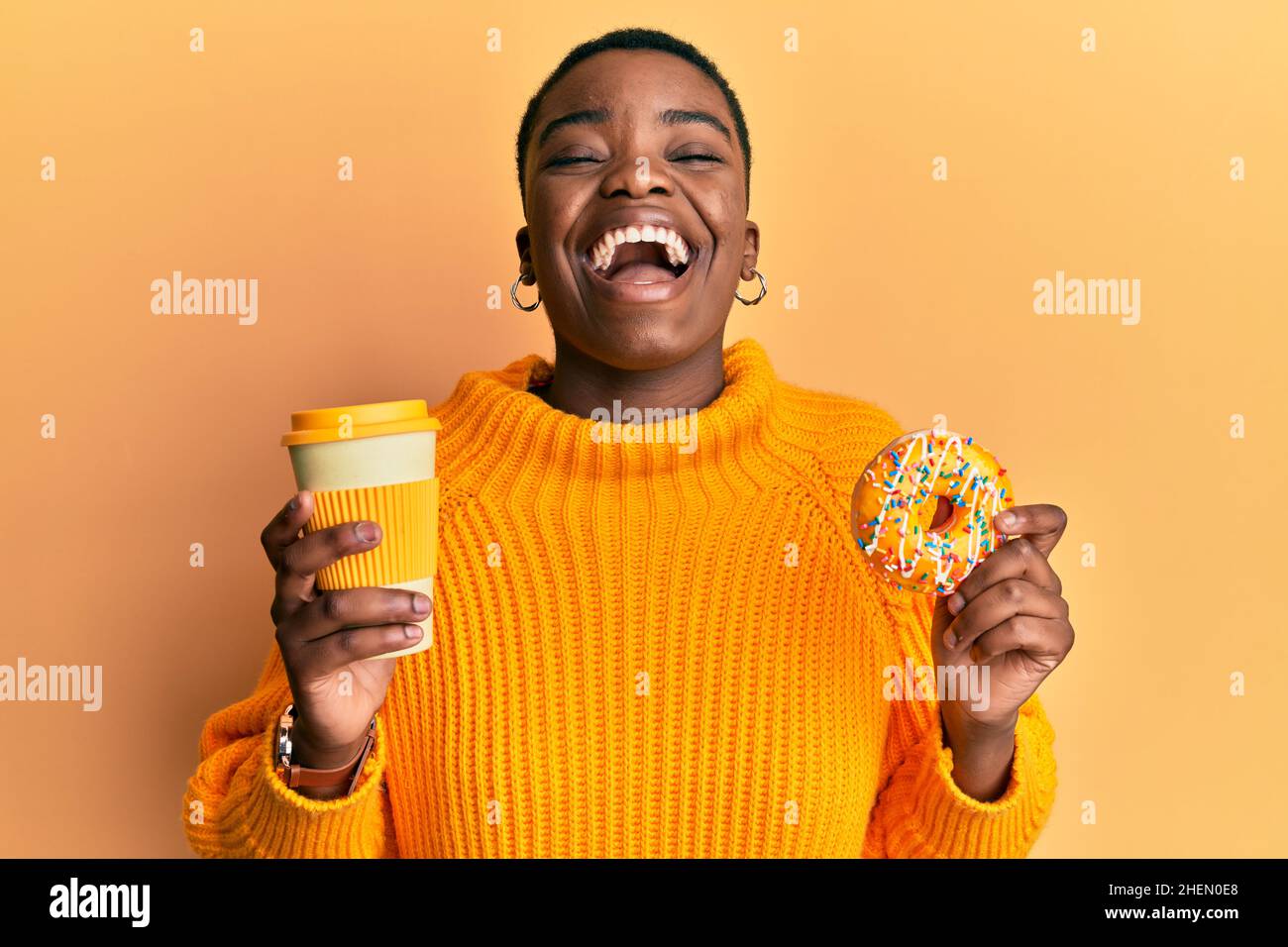 Young african american woman eating doughnut and drinking take away ...