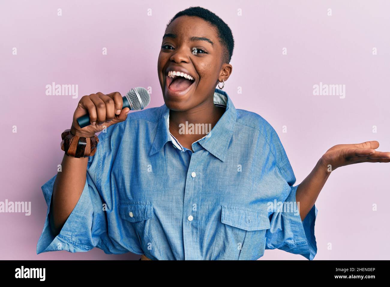 Young african american woman singing song using microphone celebrating ...