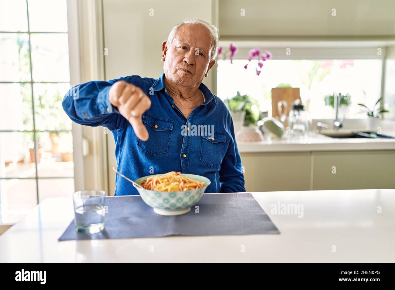 Senior man with grey hair eating pasta spaghetti at home looking ...