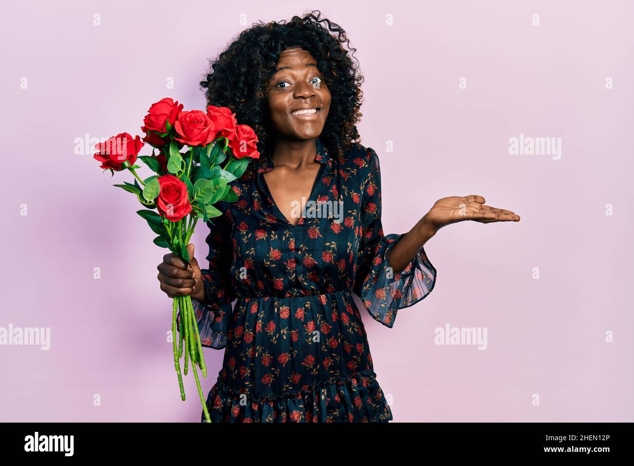 Young african american woman holding bouquet of red roses celebrating ...