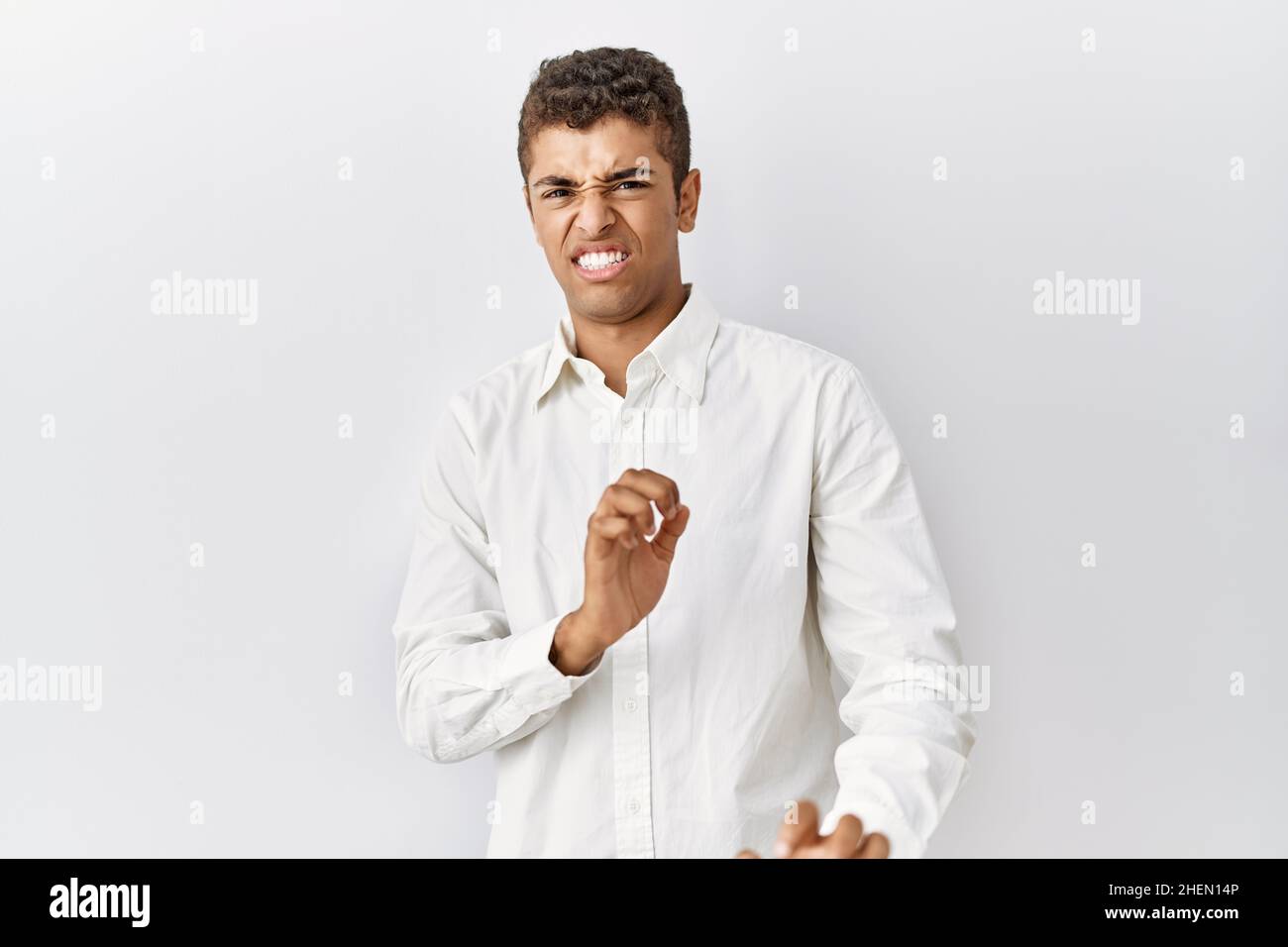 Young handsome hispanic man standing over isolated background disgusted ...