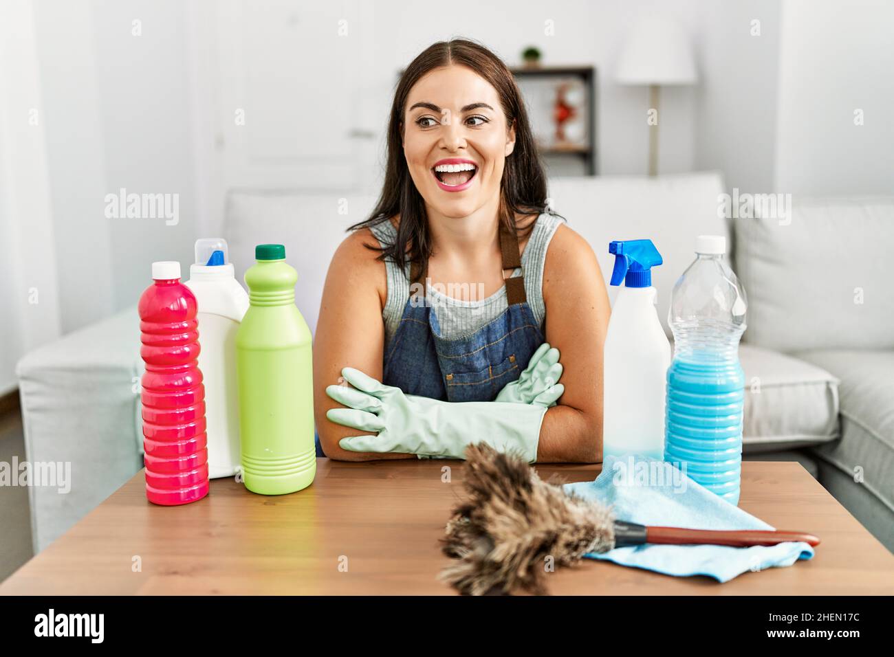 Young brunette woman wearing cleaner apron and gloves cleaning at home ...