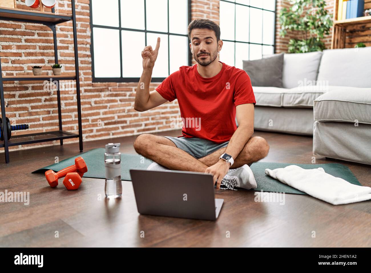 Young hispanic man watching training tutorial at home smiling with an ...