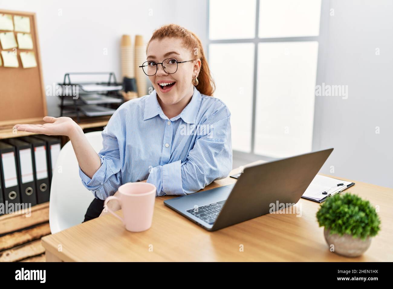Young redhead woman working at the office using computer laptop ...
