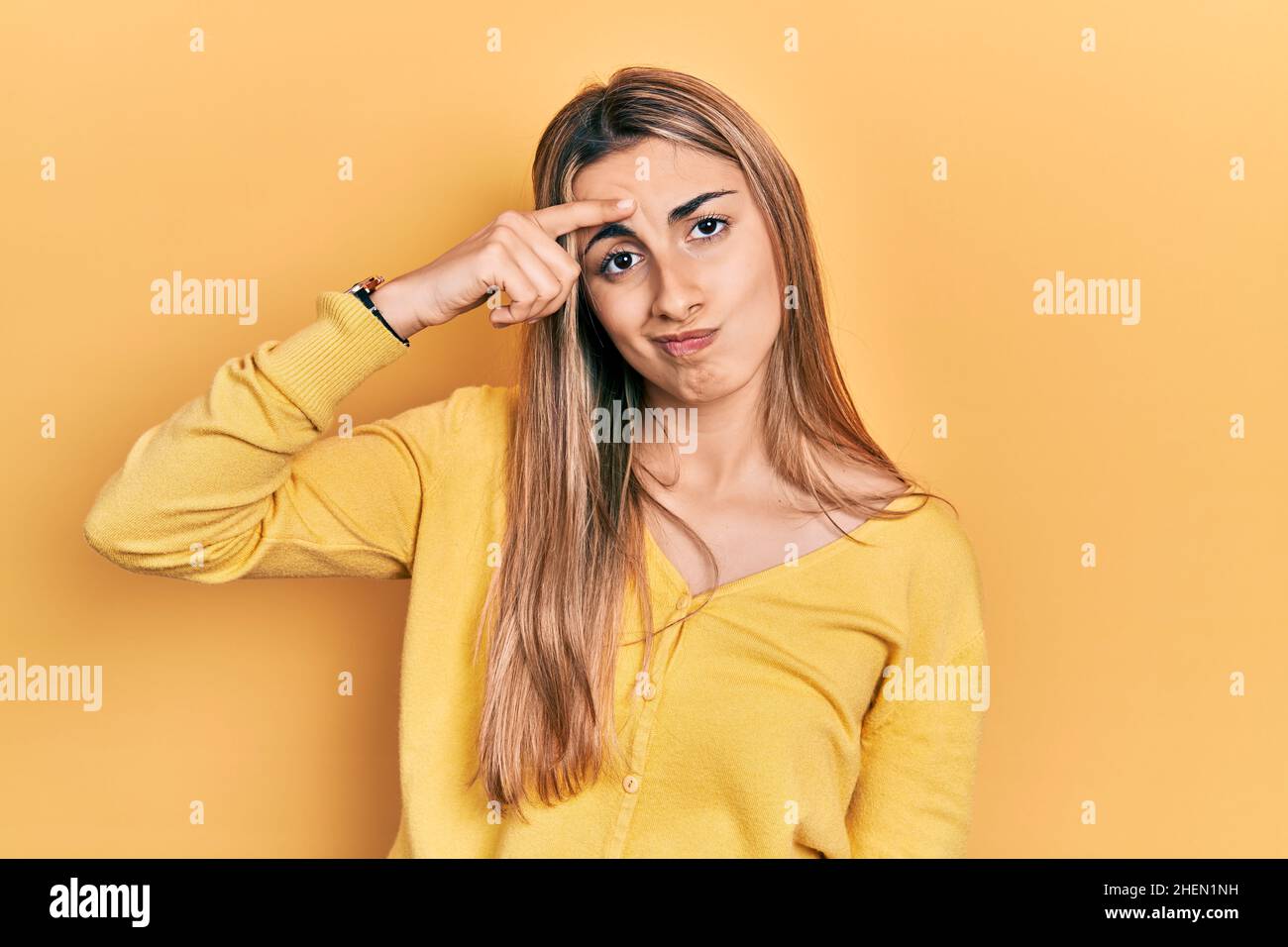 Beautiful hispanic woman wearing casual yellow sweater pointing unhappy ...