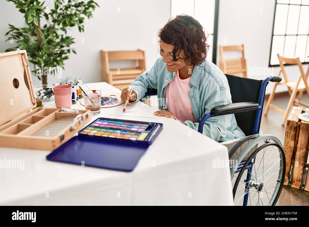 Middle age hispanic disabled artist woman drawing sitting on wheelchair ...