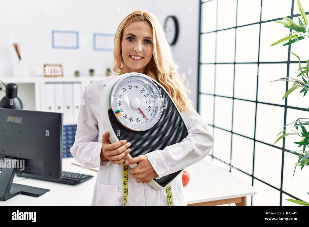 Beautiful blonde nutritionist woman holding weight machine to balance ...