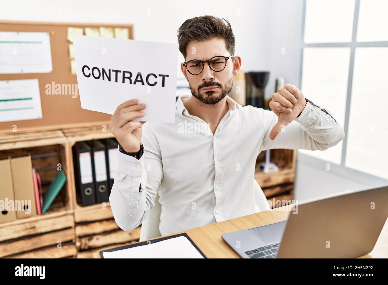 Young man with beard holding contract paper at the office with angry ...