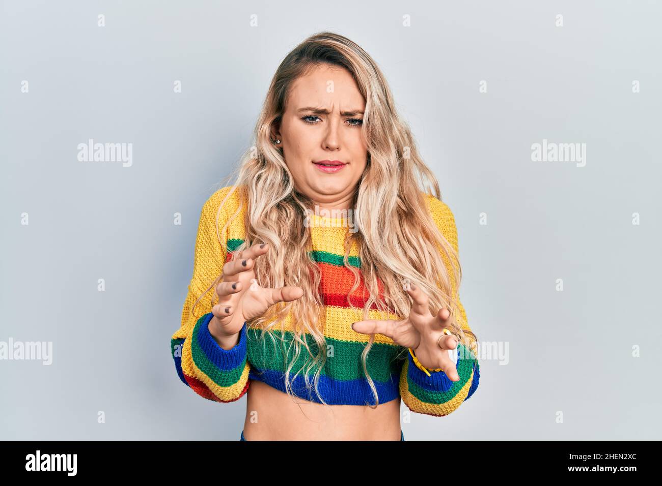 Beautiful young blonde woman wearing colored sweater disgusted ...