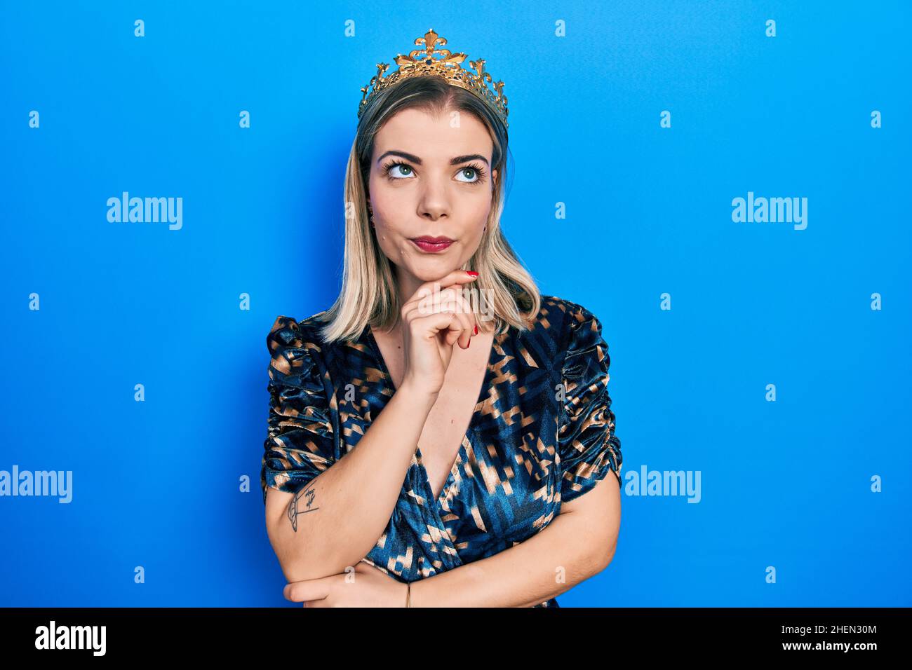 Beautiful caucasian woman wearing princess crown serious face thinking ...
