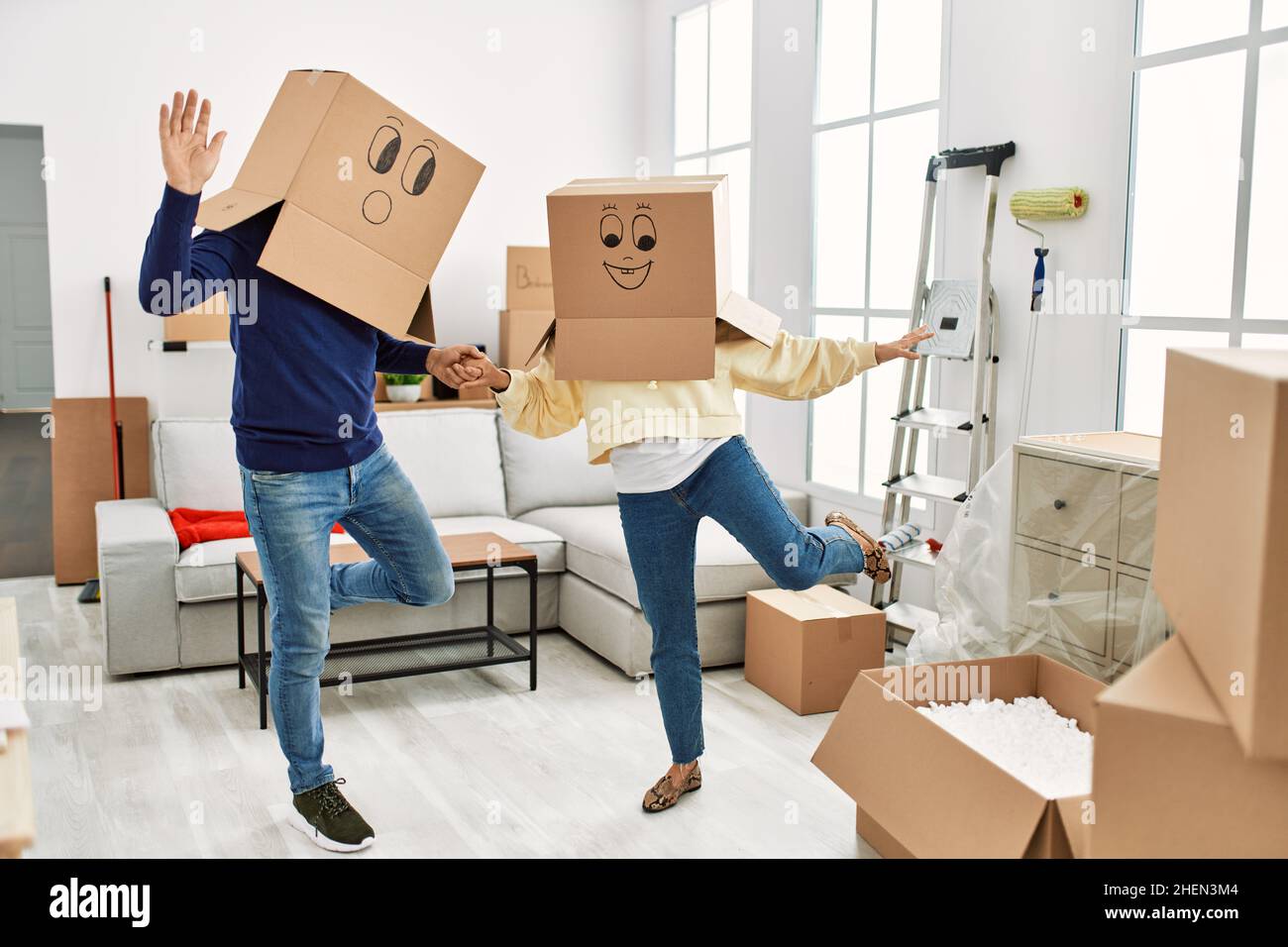 Middle age hispanic couple playing and dancing with funny cardboard ...