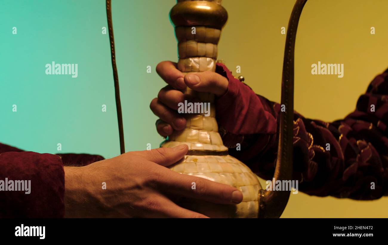 Man hands giving eastern ceramic jug on blue and yellow background ...