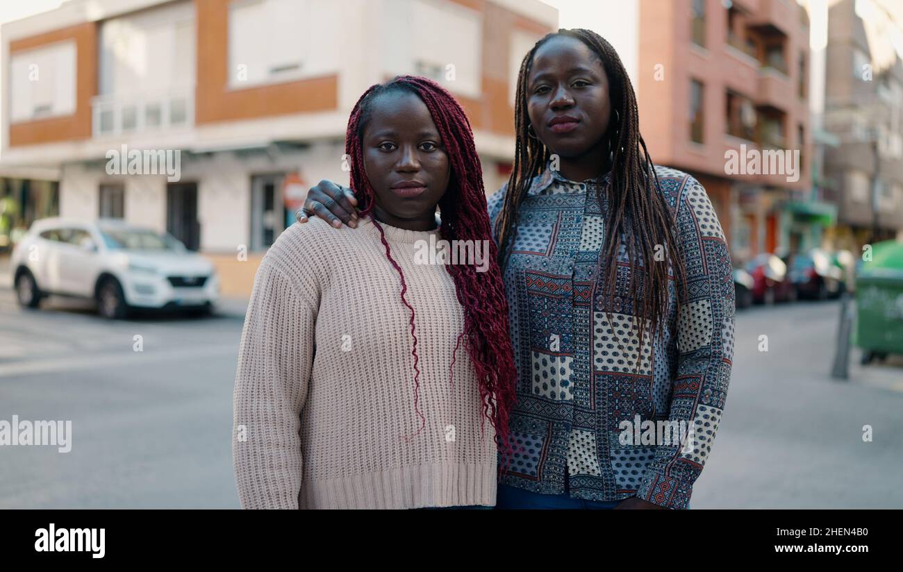 Two african american friends with serious expression hugging each other ...