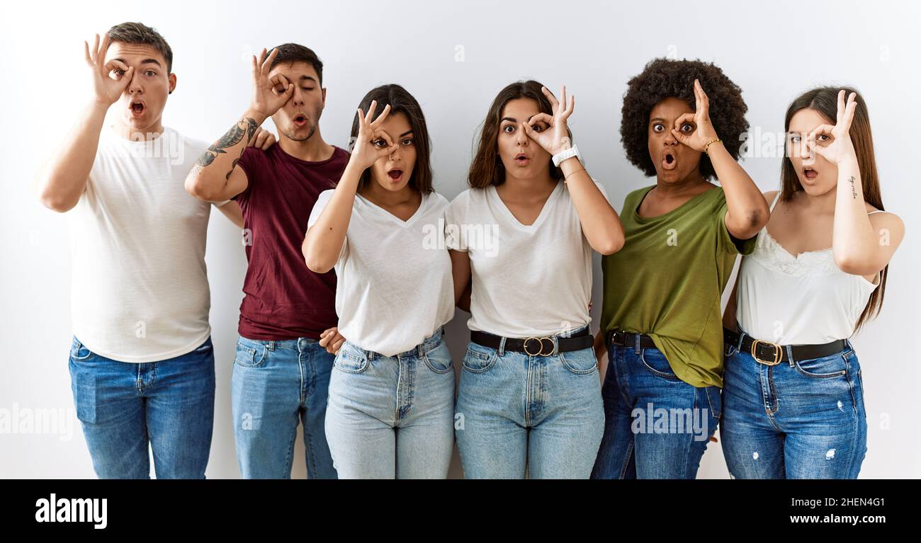Group of young friends standing together over isolated background doing ...
