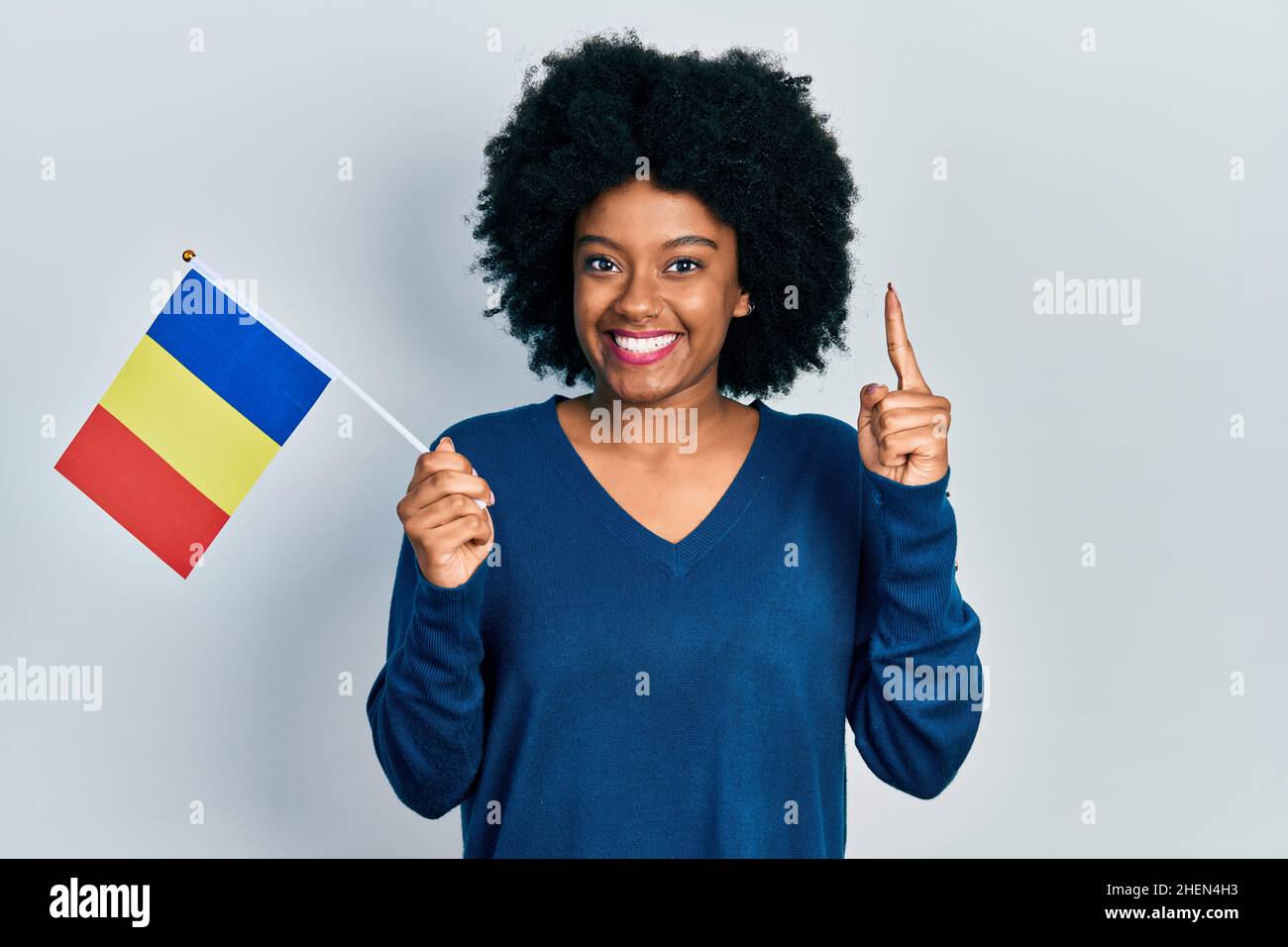 Young african american woman holding romania flag smiling with an idea ...