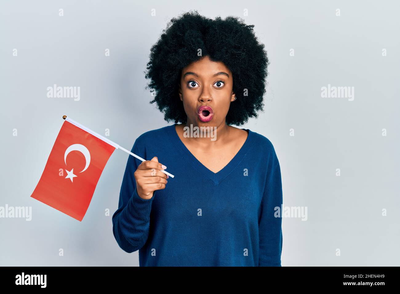 Young african american woman holding turkey flag scared and amazed with ...