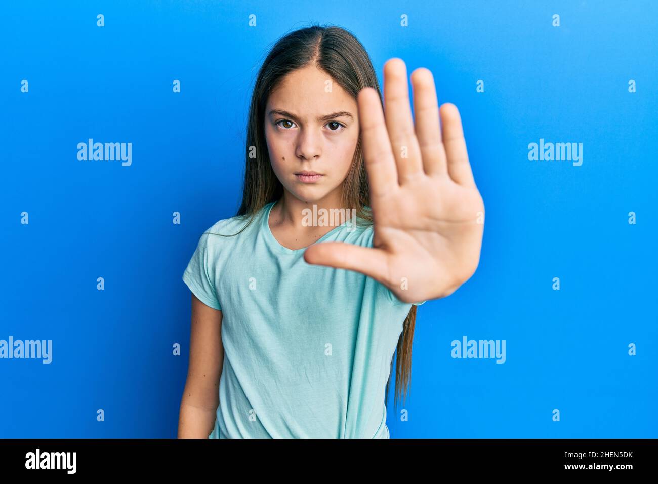 Beautiful brunette little girl wearing casual white t shirt doing stop ...