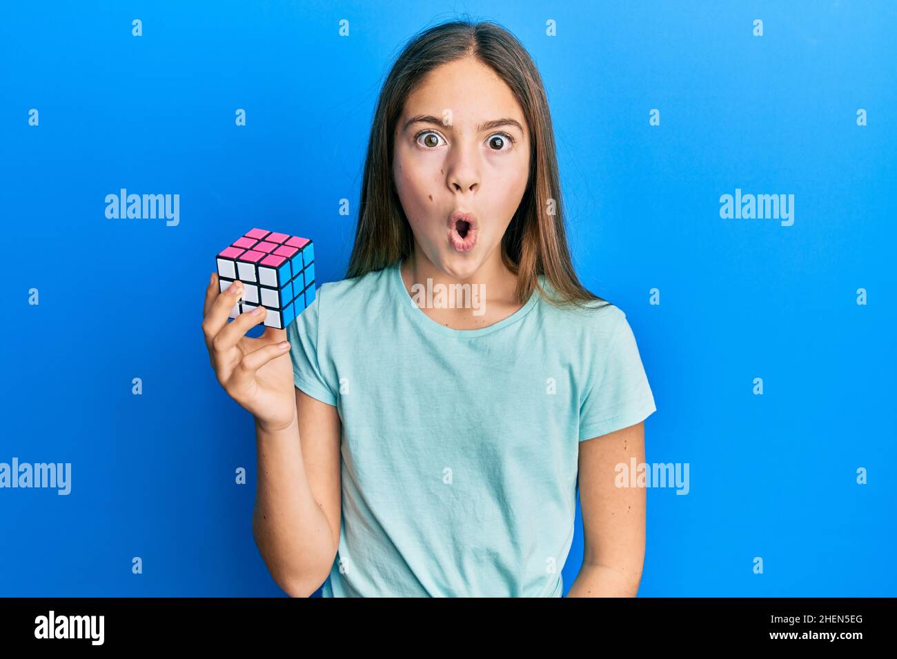 Beautiful brunette little girl playing colorful puzzle cube ...