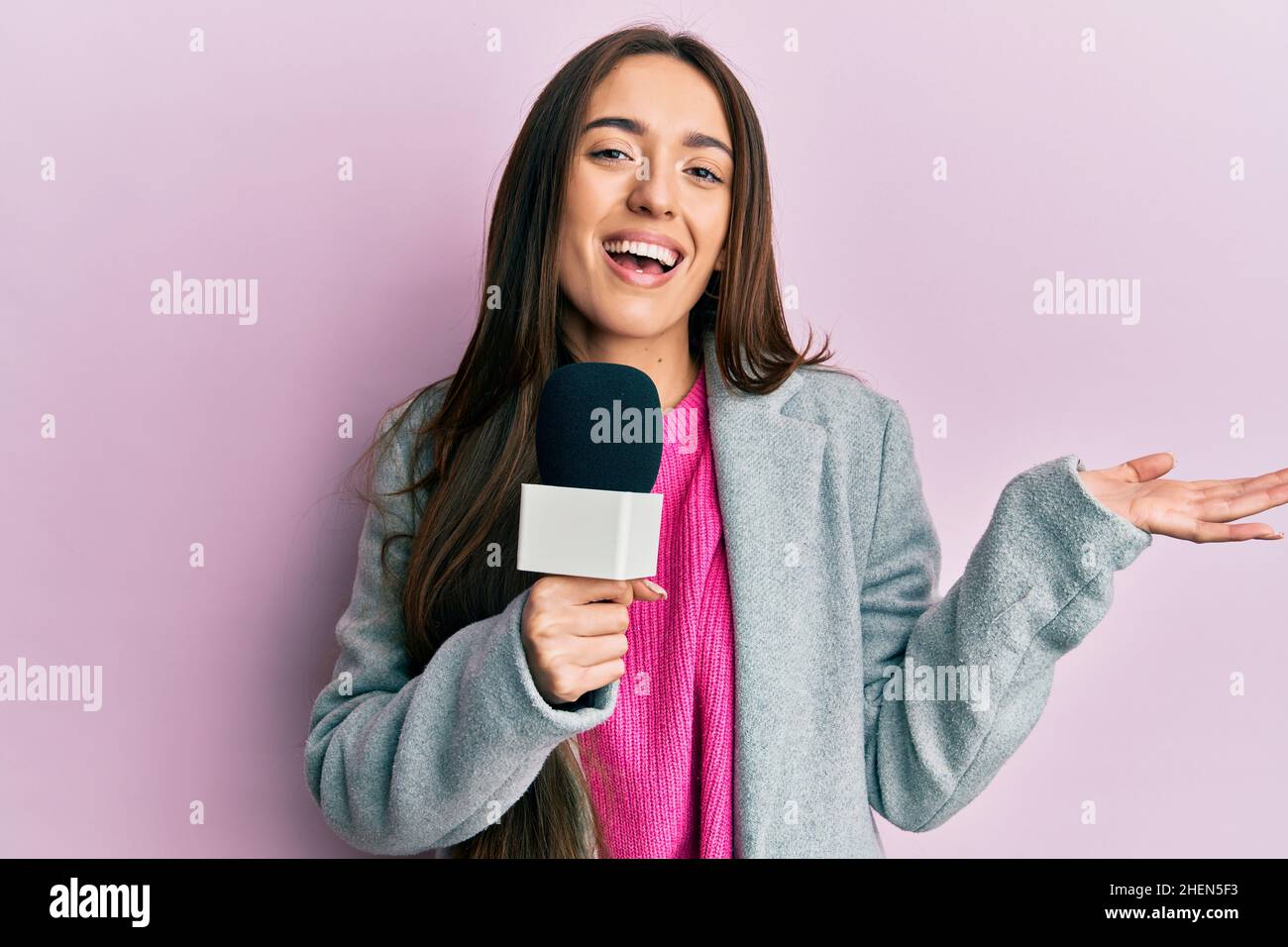 Young hispanic girl holding reporter microphone celebrating achievement ...