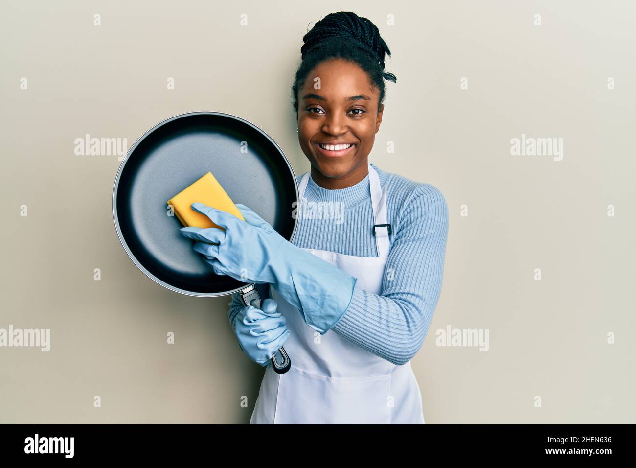 African american woman with braided hair wearing apron holding scourer ...