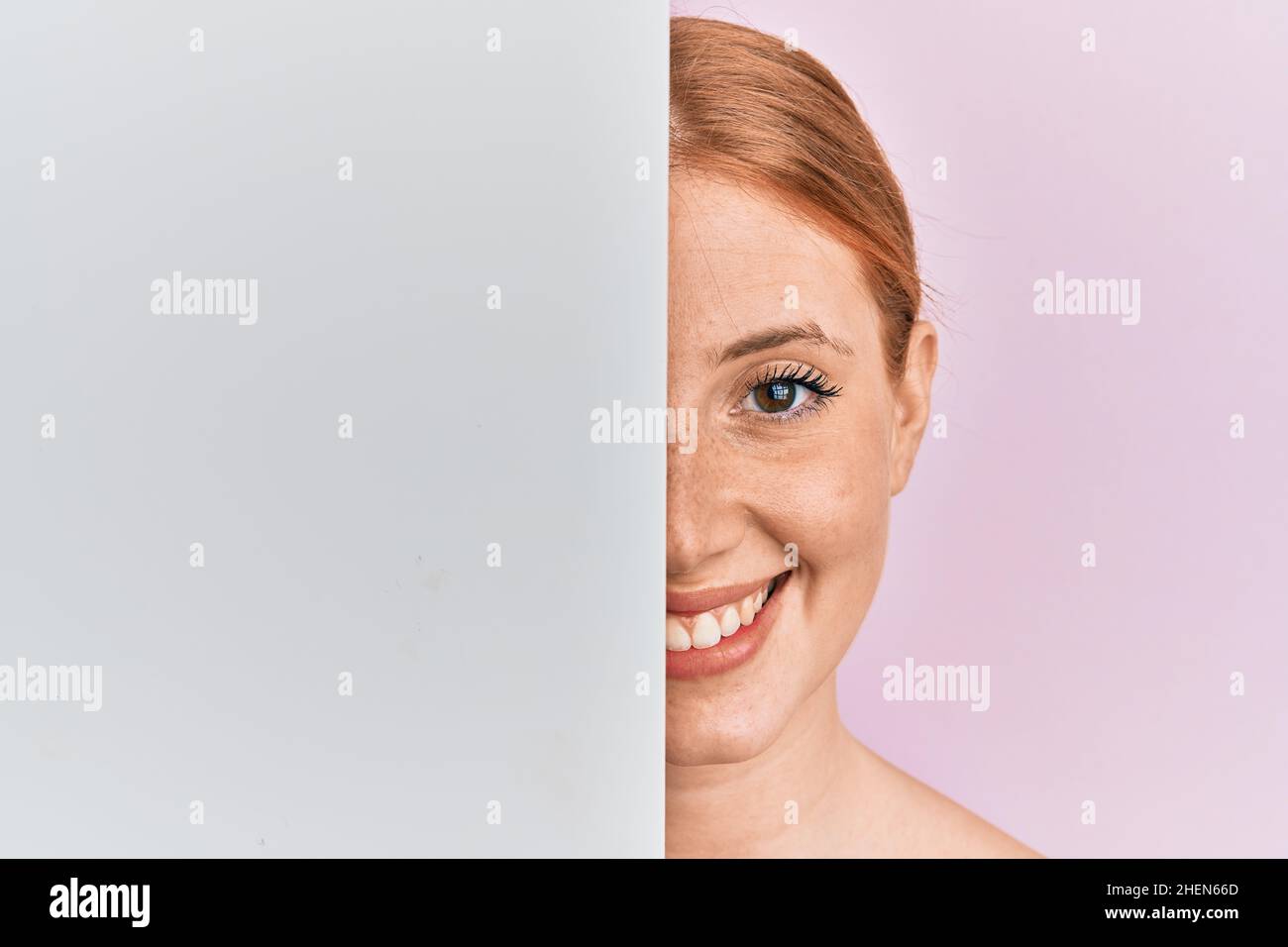 Young irish woman holding blank empty banner showing half face smiling ...