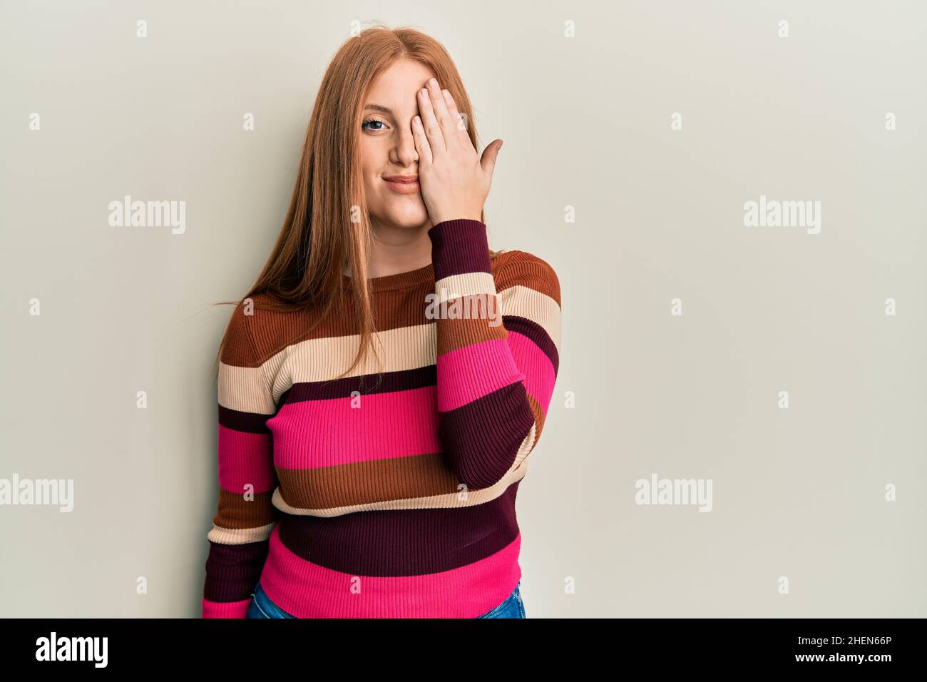 Young irish woman wearing casual clothes covering one eye with hand ...