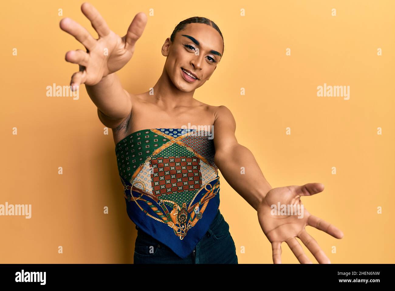 Hispanic man wearing make up and long hair wearing womans top looking ...