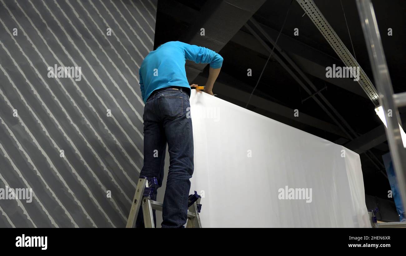 Worker builds a concert stage. Worker in blue shirt standing on ...